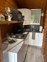 Uma cozinha compacta com micro-ondas, cafeteira e pequena geladeira.
