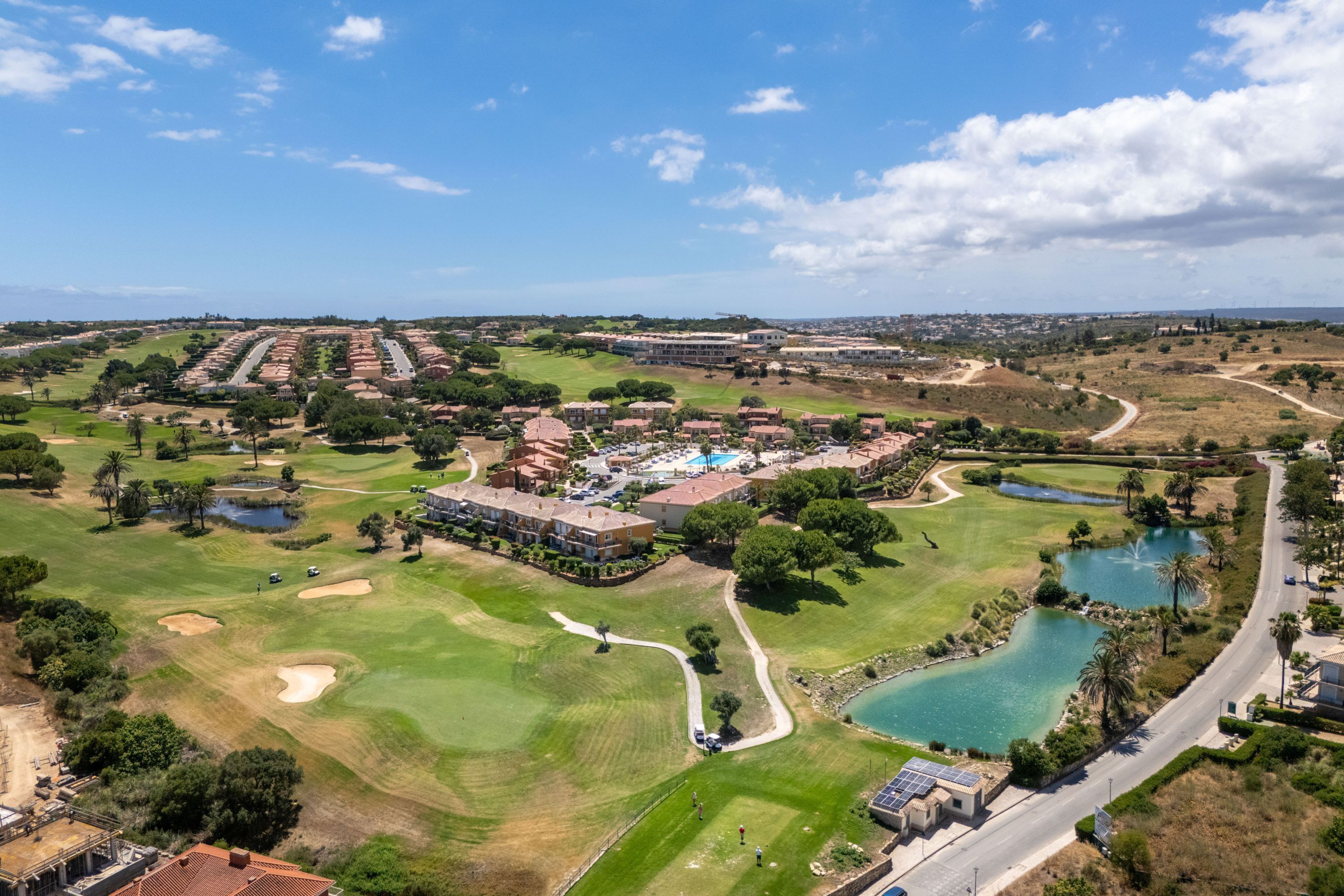 Um campo de golfe com vários buracos, um clube e uma piscina.