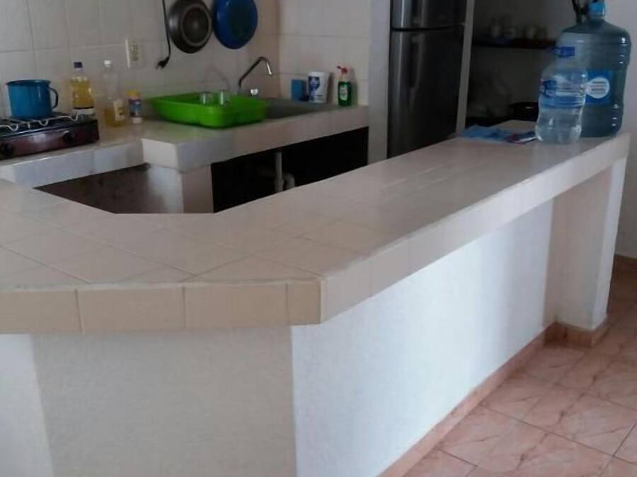 Cozinha com bancada branca, pia, micro-ondas, fogão e geladeira.