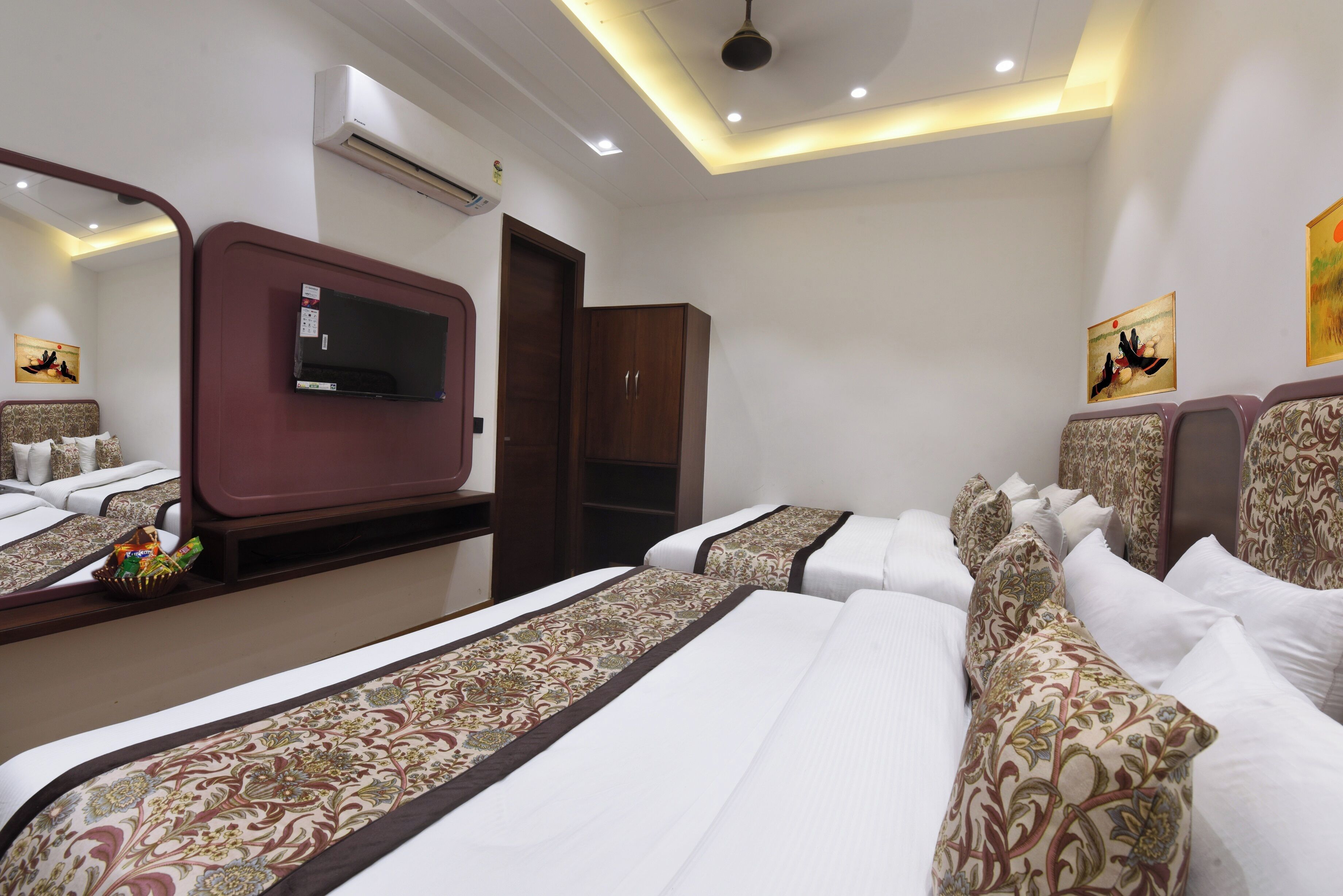 Quarto de hotel com cama, televisão, guarda-roupa e espelho.