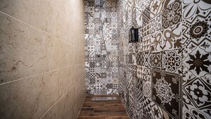 Um corredor estreito com azulejos estampados nas paredes e soalho de madeira.