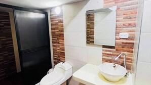 Casa de banho com sanita, lavatório e espelho.