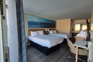 Quarto de hotel com duas camas, uma escrivaninha e uma janela grande.