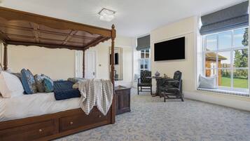 Uma cama de dossel com cabeceira de madeira, uma mesinha de cabeceira e uma poltrona com assento acolchoado.