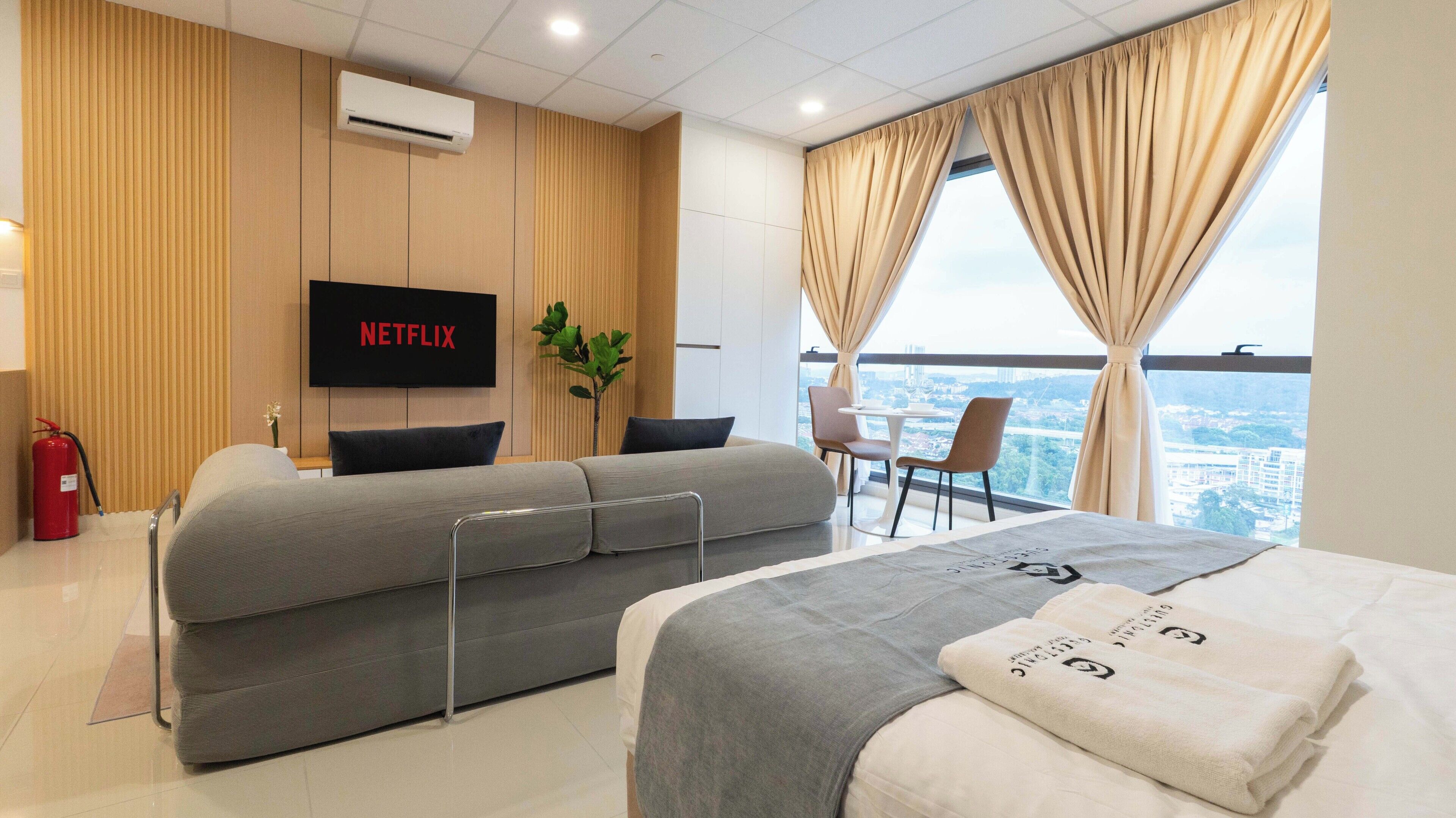 Quarto de hotel moderno com sofá, cama, mesa de jantar e vista da cidade.