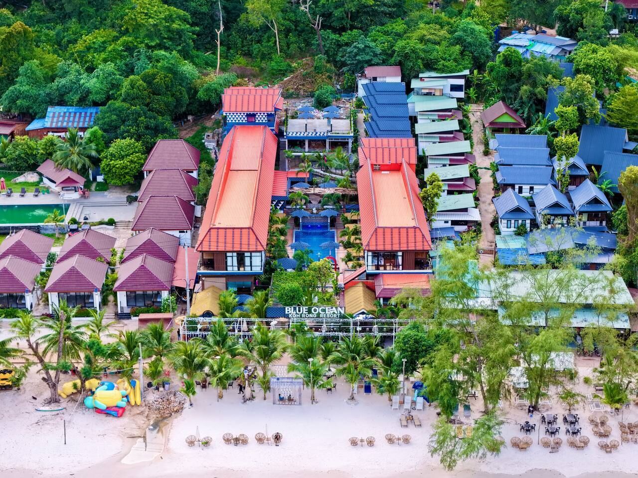 A resort with multiple buildings, a swimming pool, and a beach area.