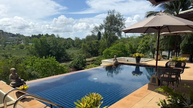 Piscina com vista para a paisagem, uma estátua de Buda e área de estar externa.