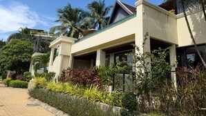 Um edifício moderno com entrada coberta, rodeado por vegetação exuberante e palmeiras.