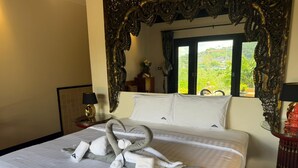 Quarto de hotel com cama de dossel, vista para o verde lá fora e um espelho decorativo.