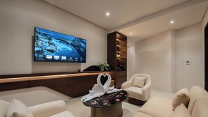 Um lobby moderno de hotel com uma grande televisão de tela plana, assentos confortáveis e uma mesa de recepção.