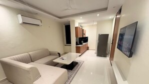 Uma sala de estar moderna com sofá, mesa de centro e televisão na parede.