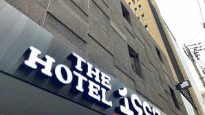 Placa de hotel com o nome 'THE HOTEL 1997' em letras iluminadas e em destaque.