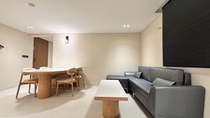 Uma sala moderna com área de jantar, sofá e mesa de centro.