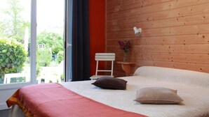 Quarto com cama, uma mesinha com um vaso e uma cadeira.