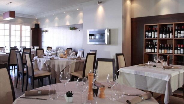 Um restaurante com várias mesas preparadas para refeições, um espaço para vinhos e decoração de interiores moderna.