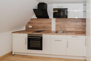Uma cozinha compacta com forno embutido, micro-ondas e pia.