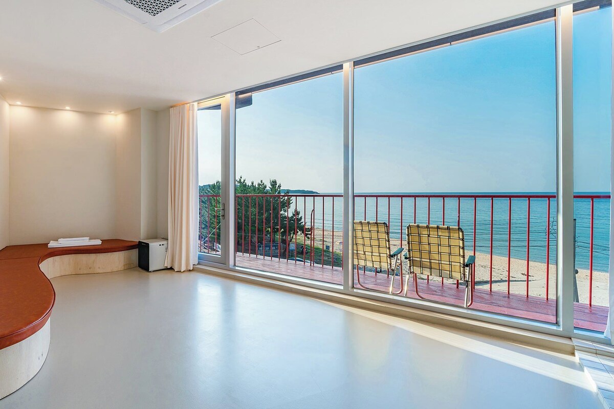 Uma varanda espaçosa com vista desobstruída para o mar, área de estar com banco e design de interiores moderno.