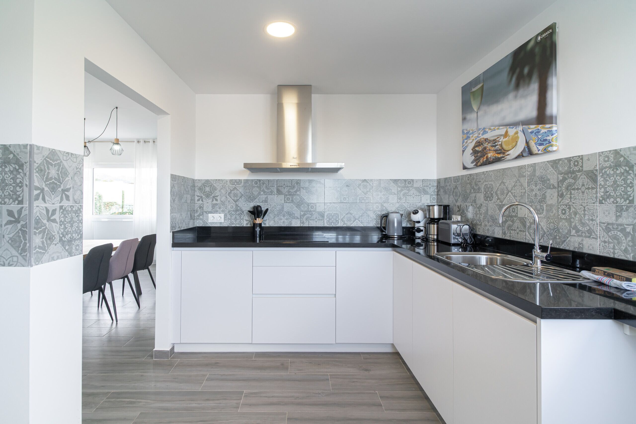 Uma cozinha moderna com uma ilha central, armários brancos e um mosaico de parede.