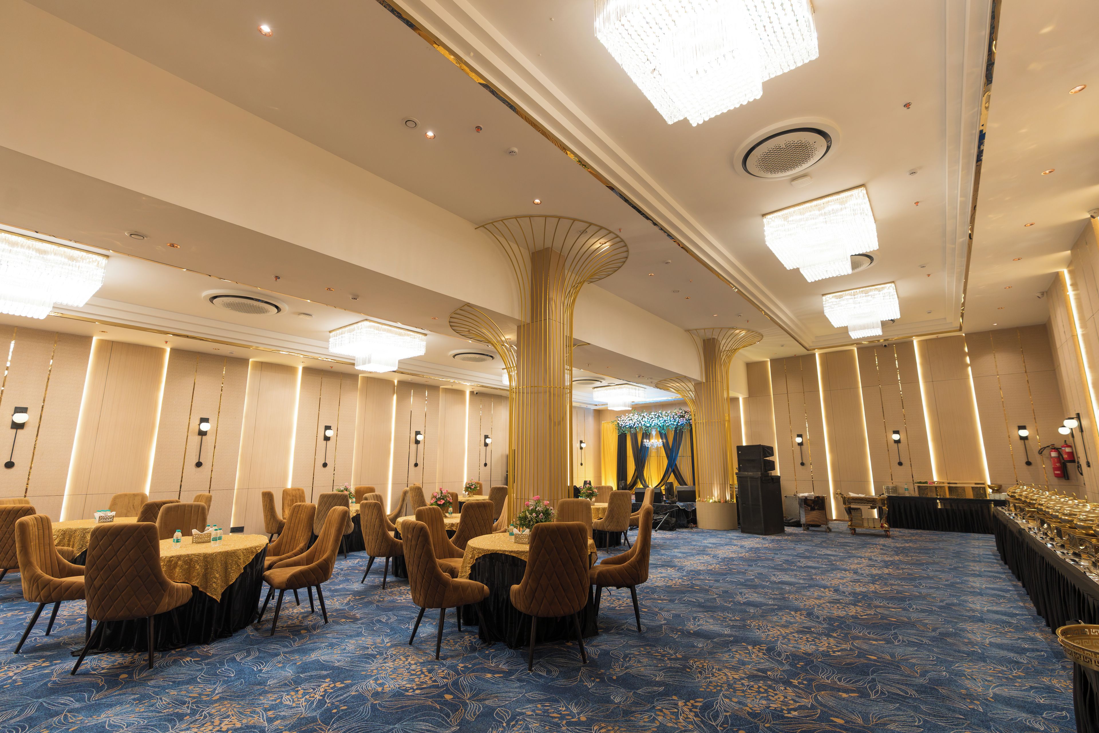 Uma sala de conferências de hotel com mesas redondas, cadeiras e um tapete azul.