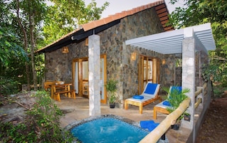 Um edifício de pedra com piscina, móveis de madeira e um pergolado.