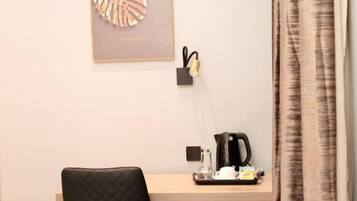 Um quarto pequeno com uma mesa, cadeira e uma obra de arte emoldurada na parede.