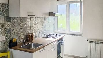 Cozinha moderna com uma ilha central, janela com vista e uma cadeira amarela.