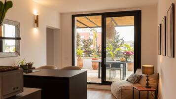Uma sala de estar moderna com sofá, uma mesinha, um abajur e vista para o pátio externo.