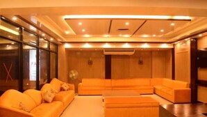 Uma sala de estar moderna com sofás laranja, uma mesa de centro e iluminação embutida no teto.
