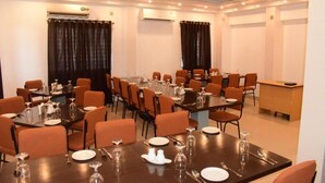 Uma sala de conferências com várias mesas e cadeiras, aparelhos de ar condicionado e uma pequena área de escritório.
