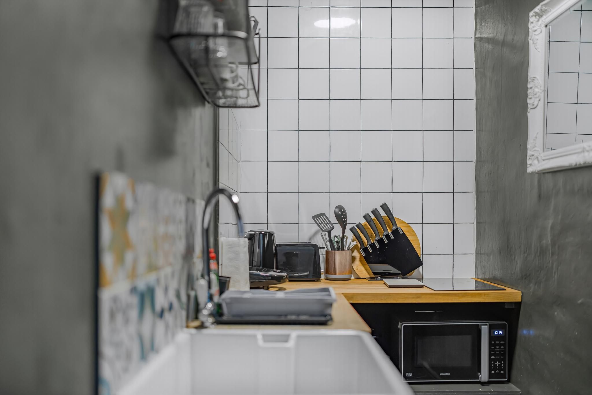 Uma cozinha com micro-ondas, torradeira e utensílios sobre o balcão.