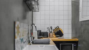 Uma cozinha com micro-ondas, torradeira e utensílios sobre o balcão.