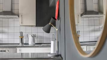 Uma cozinha com armários brancos, bancada preta e um objeto vermelho na parede.