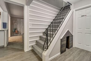 Uma escadaria com corrimão de metal, uma lareira e uma porta com a inscrição 'Master Suite'.