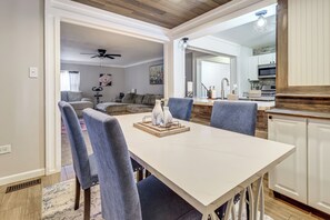 Uma sala de jantar com uma mesa branca, cadeiras azuis e um ventilador de teto.