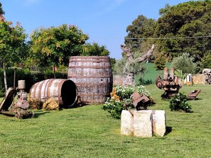 Um cenário campestre rústico com barris antigos, um trator vintage e diversos equipamentos agrícolas.