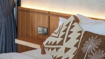 Quarto de hotel com uma cama, cabeceira de madeira, espelho e janela com cortinas.