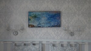 Quarto com cama, pintura na parede e um lustre.