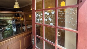 Uma porta emoldurada a vermelho com um janelão e uma luminária pendente, além de vista para o exterior.