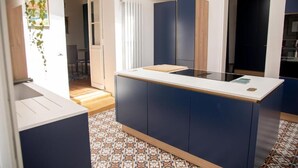 Uma cozinha moderna com armários escuros, bancada branca e chão estampado.