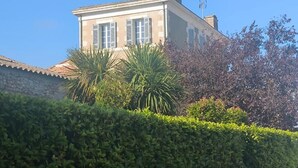 Um edifício de dois andares com fachada de pedra, chaminé e janela com persianas.