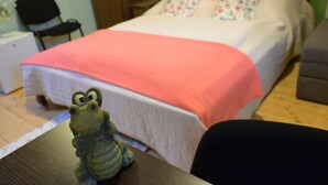 Uma cama com cobertor rosa, cabeceira de madeira e almofadas florais.