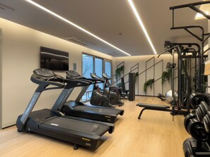 Uma academia com esteiras, aparelhos de musculação e um espelho.