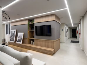 Uma sala de estar moderna com televisão de tela plana, estantes de madeira e um sofá.