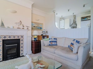 Uma sala de estar com lareira, um sofá com almofadas decorativas, uma luminária e um quadro na parede.