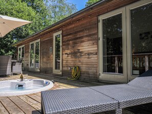 Uma cabana de madeira com hidromassagem, área de estar ao ar livre e grandes janelas.