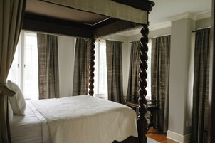 Uma cama com dossel em um quarto com janelas amplas e cortinas.