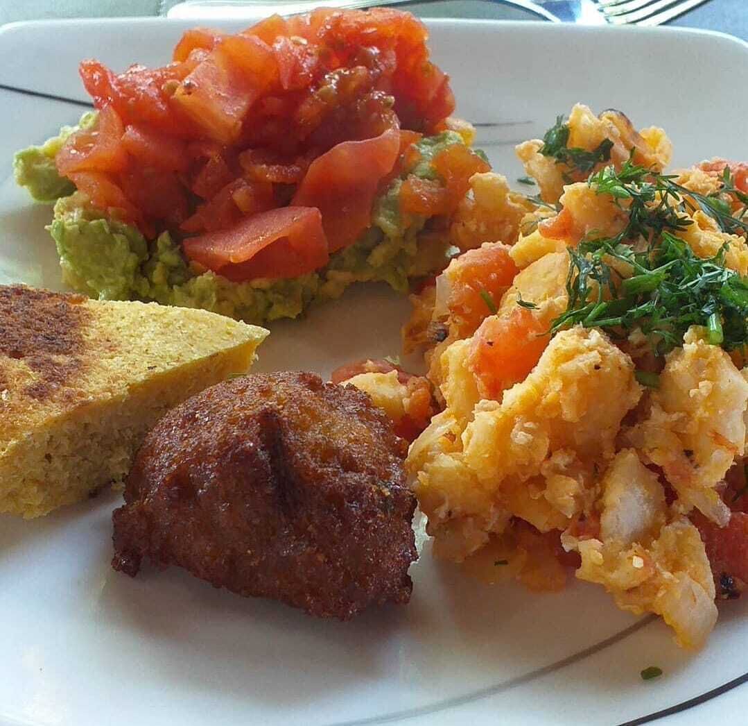 Um prato com ovos mexidos, uma fatia de torrada e um hambúrguer.