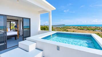 Quarto de hotel moderno com varanda, banheira de hidromassagem e vista para o mar e paisagem.