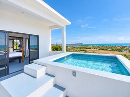 Quarto de hotel moderno com varanda, banheira de hidromassagem e vista para o mar e paisagem.