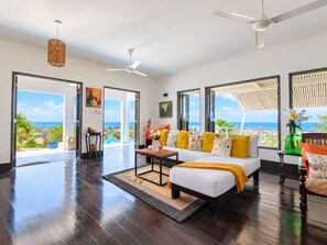 Ampla sala de estar com sofá, mesa de centro e vista para o mar.